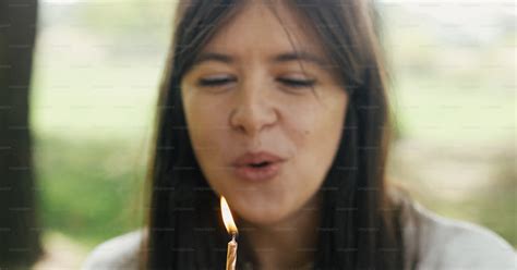 파티 모자를 쓴 세련된 행복한 여자가 촛불을 태우고 생일 케이크 조각을 들고 소원을 빌고 있다 야외 피크닉 파티에서 생일을 축하합니다 사진 Unsplash의 생일