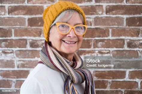겨울 모자와 스카프를 입고 미소 짓는 시니어 여성의 초상화 벽돌 벽 배경 겨울에 대한 스톡 사진 및 기타 이미지 겨울 노인 백인종 Istock