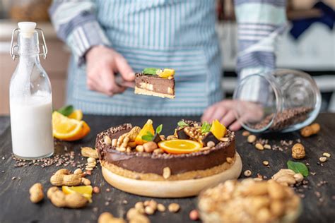 과자 요리사 손에 오렌지와 땅콩 초콜릿 케이크의 조각을 들고 채식주의자를 위한 건강 한 생 디저트 과일에 대한 스톡 사진 및 기타 이미지 Istock