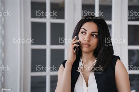 사랑스럽고 차분한 아프리카계 미국인 젊은 여성이 집에 서서 믿을 수 없다는 표정으로 옆을 쳐다본다 사무실에서 핸드폰을 사용하는