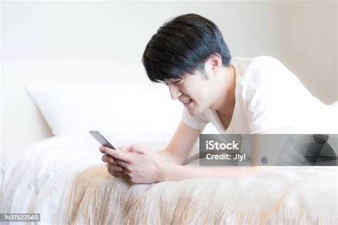 현대 가족 침실 침대에 등을 대고 누워 있는 동안 전화를 사용하는 젊은 동아시아 남자 스톡 사진 전화 사용에 대한 스톡 사진 및 기타 이미지 Istock