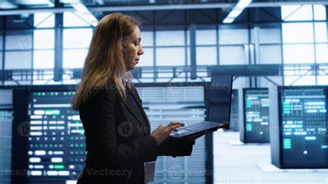 Woman Walking In High Tech Facility Using Laptop To Patch Network Issues Leading To Slow Data