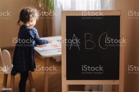 사랑스러운 어린 소녀는 테이블에 앉아 놀고 놀기 귀여운 작은 아이는 검역 중에 집에서 놀고 공부합니다 초점에 서면 편지 Abc