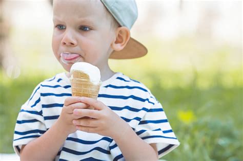 귀엽고 행복한 어린 소년은 더운 여름날에 야외에서 아이스크림을 먹는 아름다운 미소와 더러운 얼굴로 먹습니다 어린이는 여름 방학 동안 달콤한 디저트를 즐깁니다 2 3 살에