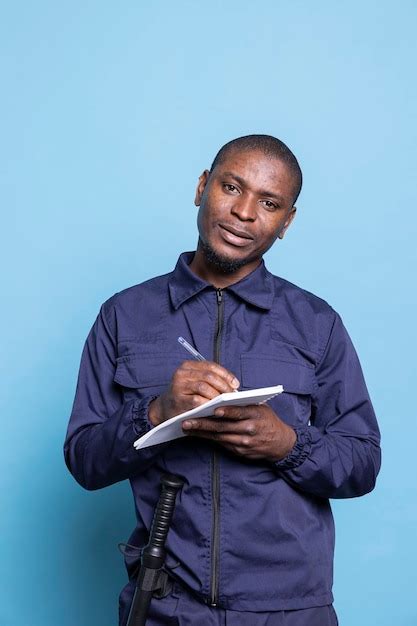 Security Agent In Safeguarding Uniform Takes Notes On A Notebook Free