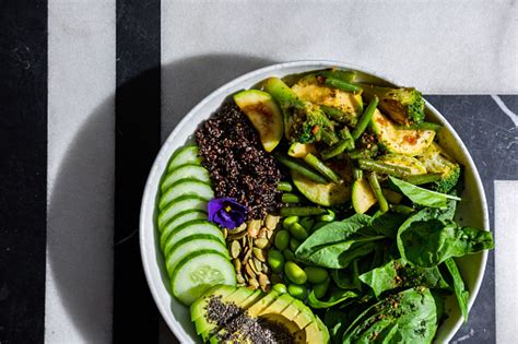 토마토 브로콜리 바질 브로콜리 호박 오이 아스파라거스 콩 참깨 수박 씨앗 아보카도 콩 보라색 꽃을 곁들인 치아 샐러드 편지가있는 배경에 접시에 0명에 대한 스톡 사진 및