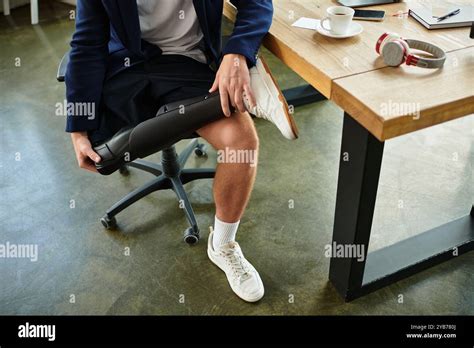 A Young Businessman With A Disability Adjusts His Prosthetic Limb While