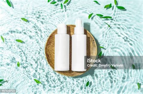 하얀 화장품 병은 푸른 물을 떠 다니는 나무 접시에 모형을 가지고 있습니다 크림 젤 강장제 클렌저 로션 및 기타 전문 화장품 제품 프레젠테이션 공란에 대한 스톡 사진 및
