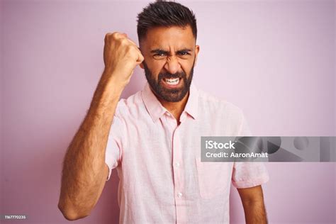고립 된 분홍색 배경 에 서 캐주얼 셔츠를 입고 젊은 인도 남자는 분노와 함께 외치는 동안 좌절과 분노를 제기 주먹 분노와 공격적인 개념 감정에 대한 스톡 사진 및 기타