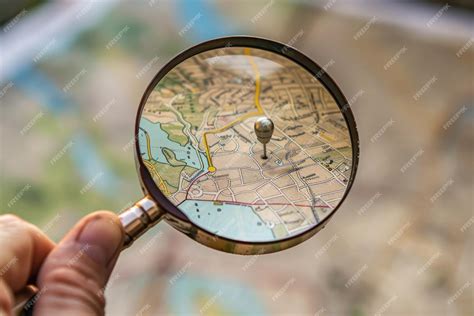 A Hand Holding A Magnifying Glass Over A Pin Location Map Indicating Attention To Detail In Trip