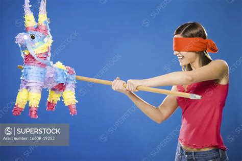 Woman With Blindfold Hitting Pinata With Stick Superstock