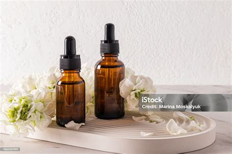 퍼스널 케어 용 화장품이 담긴 두 개의 화장품 병은 아치와 꽃 형태의 흰색 석고 트레이에 놓여 있습니다 정면도 강단에 대한 스톡 사진 및 기타 이미지 Istock