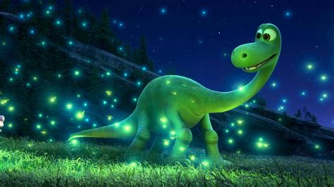 Download A Green Cartoon Dinosaur Standing On Top Of A Hill Taking In