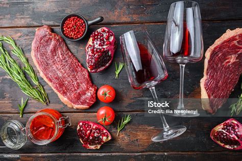 로즈마리 매콤한 칠리 오일 석류 레드 와인 한 잔을 곁들인 생 피칸하 소고기 스테이크가 오래된 어두운 나무 테이블 꼭대기