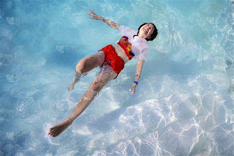 在一个炎热的夏天一个美丽的年轻女孩在游泳池里仰面漂浮
