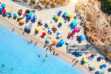 모래 해변에 화려한 우산의 공중 전망 여름에 일출에 푸른 바다에서 수영하는 사람들 사르데냐 이탈리아 맑은 푸른 물이 있는 열대