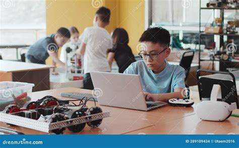 Schoolboy Coding On A Laptop Sitting At The Desktop With A Joystick Vr Headset And Chassis Of A