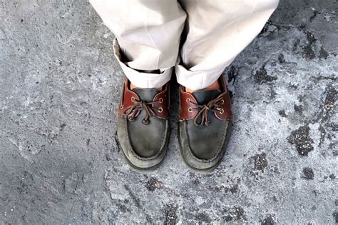 맨 위를 보기 위해 콘크리트 바닥에 고립 된 갈색 및 녹색 신발을 착용 한 남자 패션 남성은 어떤 사용에 대 한 좋은 시멘트 바닥 배경에 청바지와 빈티지 부츠 다리입니다