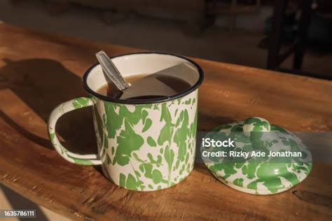 녹색 추상 패턴의 에나멜 철제 유리에 담긴 뜨거운 차 또는 커피 햇빛이 비치는 나무 테이블에 있는 오래된 가전제품 건강한 생활방식에 대한 스톡 사진 및 기타 이미지 Istock