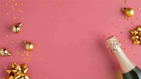 크리스마스 축 하 개념입니다 샴페인 병 황금 공 장식 반짝이 분홍색 배경에 색종이가 있는 평평한 평신도 구성 크리스마스