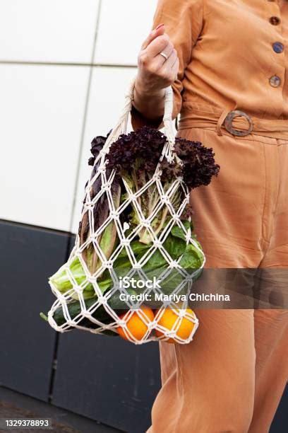 소녀는 비닐 봉지없이 야채 채소와 메쉬 쇼핑 백을 들고있다 제로 폐기물 플라스틱 무료 환경 친화적 인 개념 수제 마크라메 백 지속 가능한 라이프 스타일 가방에 대한 스톡