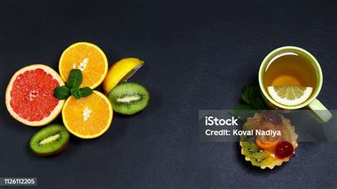 다양 한 과일 자 몽 오렌지 키 위 레몬 민트 케이크 달콤한 과일 디저트 모여서 혈 암 보드에 차 한잔 건강의 개념은 공간