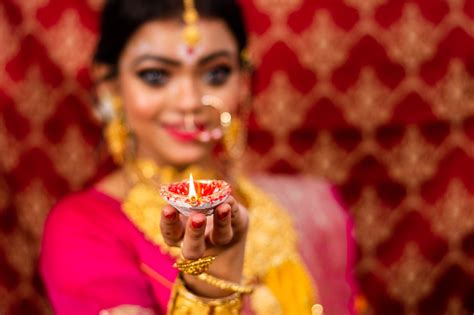 디왈리를 계기로 꽃을 배경으로 오일 램프 조명이나 디야를 들고 전통 사리 드레스를 입은 아름다운 젊은 인도 여성 Onam에 대한