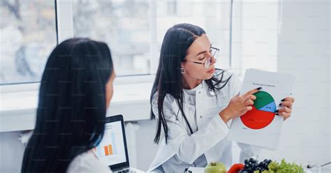 그래프가있는 여성 영양사는 사무실에서 실내에서 환자에게 상담을 제공합니다 사진 Unsplash의 우크라이나 이미지