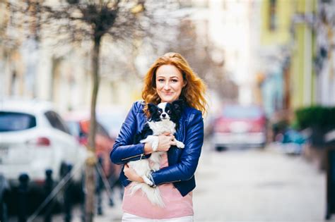 제목 남자 고 개입니다 얼굴에 주 근 깨와 빨간 머리 젊은 백인 여자 흑인과 백인 얽히고 설킨 치와와 품종 개를 보유 하고있다 블루 가죽 자 켓 입은 여자 봄 바쁜 거리에