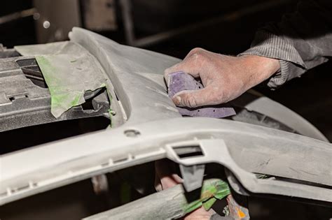 소년은 자동차 수리점에서 연마 종이의 도움으로 사고 후 페인팅을 위한 차체 요소를 준비 합니다 충돌 후 복구 범퍼 교통사고 충돌 사고에 대한 스톡 사진 및 기타 이미지