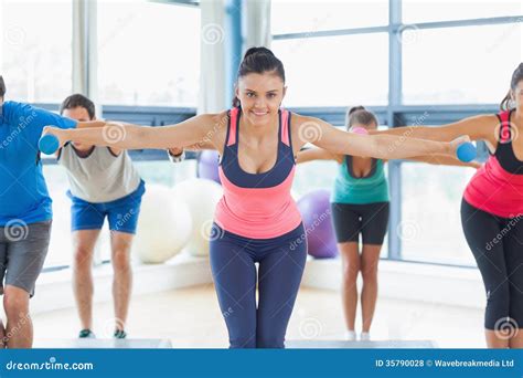 Instructor With Fitness Class Performing Step Aerobics Exercise With