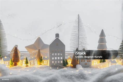 분위기 있는 미니어처 겨울 마을 세련된 작은 도자기 집과 저녁에 빛나는 조명이 있는 눈 담요 위의 크리스마스 나무 나무 크리스마스 현대 배경입니다 즐거운 휴일 보내세요 0