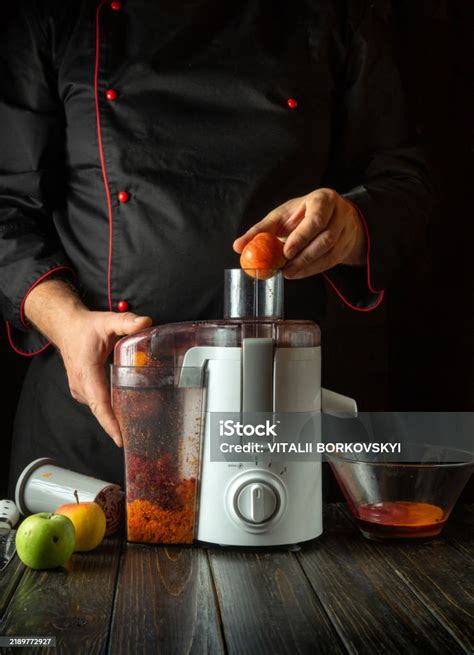요리사는 생 사과를 전기 과즙 짜는기구에 수동으로 추가합니다 저녁 식사를 위해 호텔 부엌 테이블에서 건강한 과일 음료 만들기 검정색 배경에 대한 스톡 사진 및 기타 이미지