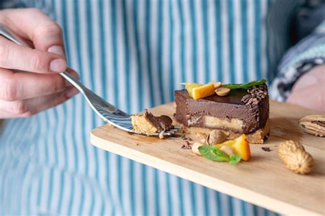 오렌지 민트 잎과 견과류와 초콜릿 케이크의 조각을 포크로 손 나누기 채식주의자를 위한 건강 한 생 디저트 개념에 대한 스톡 사진