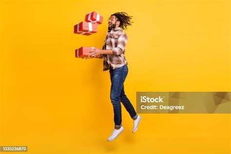 밝은 노란색 색상 배경에 고립 된 선물 상자를 들고 점프 하는 매력적인 쾌활한 남자의 전체 길이 바디 사이즈 보기 긍정적인 감정 표현에 대한 스톡 사진 및 기타 이미지