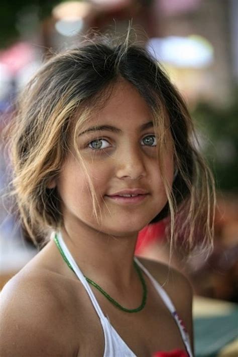 A Close Up Of A Person Wearing A White Tank Top And Necklace With Blue Eyes