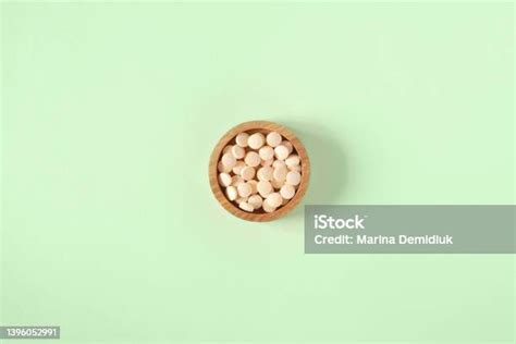 알약과 녹색 잎의 샷 바로 위에 녹색 중립 색상 배경에 나무 그릇에 정제 동종 요법 의학 허브 식물이있는 유기농 의료 캡슐 테이블 상단 보기 공간 복사 0명에 대한 스톡