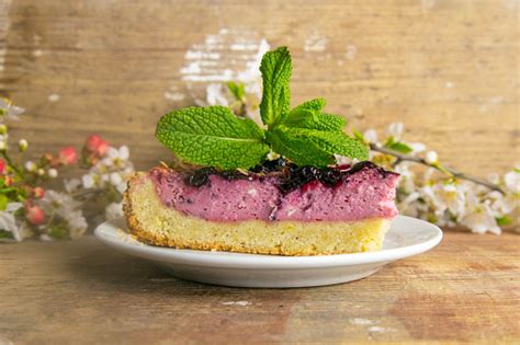 흰색 꽃이 있는 흰색 접시에 거울 유약 장식 베리와 민트 잎블루 베리 무스 케이크 조각 가까이에 나무 테이블에 있습니다 상위 조회수 0명에 대한 스톡 사진 및 기타 이미지