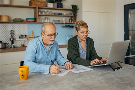 고령의 부부가 가계 지출 또는 세금을 관리하고 월별 예산을 관리하고 컴퓨터 전자 뱅킹 애플리케이션에서 세금 또는 청구서를 지불하고 투자를 계획합니다 2명에 대한 스톡 사진