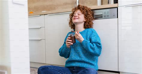 캐주얼 옷을 입은 아름다운 젊은 빨간 머리 소녀는 국내 요리의 나무 바닥에 앉아 맛있는 초콜릿 스프레드를 맛보고 있습니다 사진 Unsplash의 즐거움 이미지