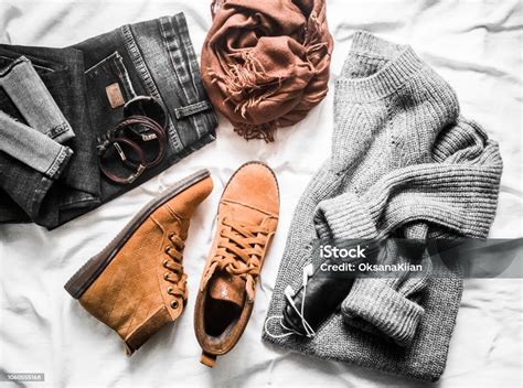 여자의 차림새가 겨울 옷청바지 회색 스웨터 특대 갈색 스웨이드 부츠의 집합입니다 세련 된 캐주얼 옷 산책 플랫 하다 밝은 배경에