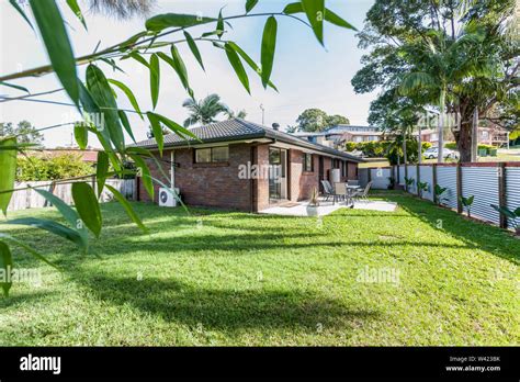 Fenced Backyard Area With Lush Green Grass A Set Of Chair And Table