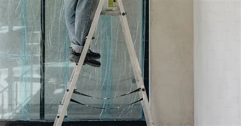 벽에 그림을 그리는 사다리 위에 서 있는 남자 사진 Unsplash의 개장 이미지