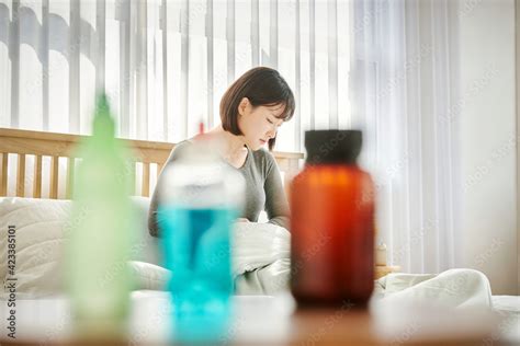 아픈 여자가 침대에 앉아서 고통을 느끼고 있음 감기 두통 복통 생리통 фотография Stock Adobe Stock