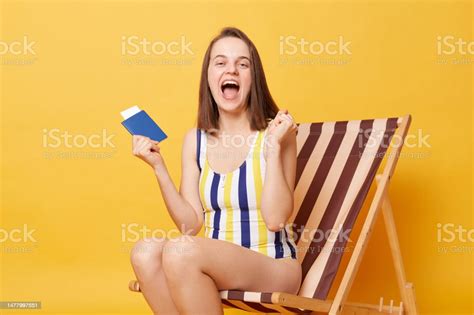 갑판 의자에 앉아 줄무늬 수영복을 입고 여권과 티켓을 손에 들고 오랫동안 기다려온 여행을 즐기고 여행하고 리조트에서 여가 시간을 즐기는 흥분된 여성의 실내 장면 30 34