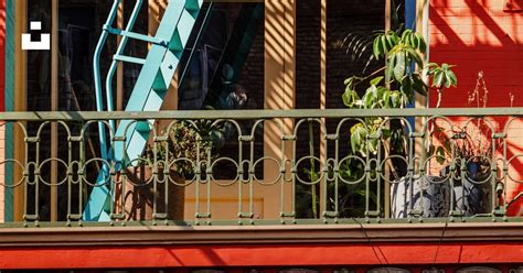 녹색 창문과 파란색 사다리가 있는 빨간색 건물 사진 Unsplash의 무료 난간 이미지