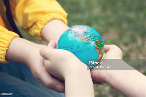 노란 비옷을 입은 어린이 소녀와 공원이나 숲에서 야외에서 손에 지구본을 들고 있는 소년 세계 지구의 날 개념입니다 녹색 에너지 재생 가능하고 지속 가능한 자원 지구를
