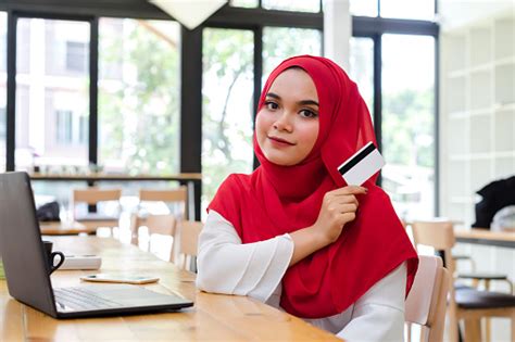 젊은 무슬림 사람들의 초상화 카페 또는 커피숍에서 신용 카드를 보여주는 빨간 히 잡을 착용 하 고 있습니다 쇼핑 온라인 컨셉