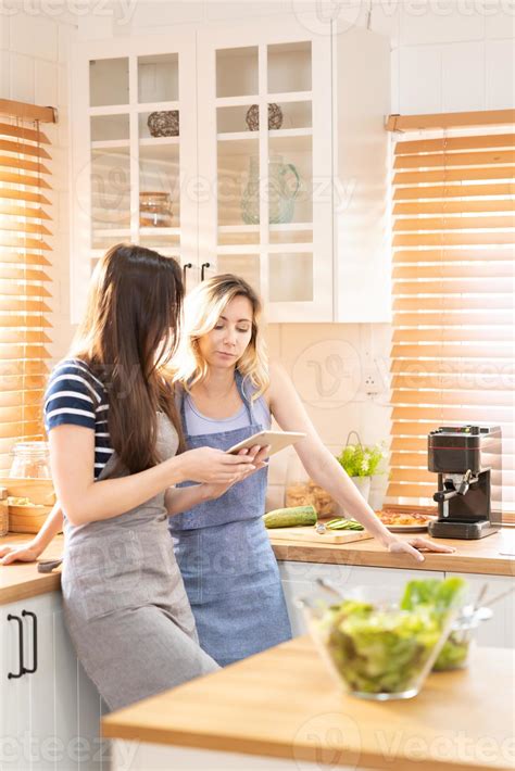 Beautiful Lesbian Couple Cooking Healthy Food Looking On Digital