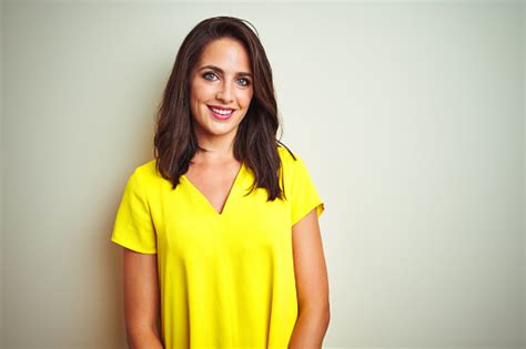 얼굴에 행복하고 시원한 미소와 흰색 고립 된 배경 위에 서 노란색 티셔츠를 입고 젊은 아름다운 여성 운이 좋은 사람 T 셔츠에 대한 스톡 사진 및 기타 이미지 Istock